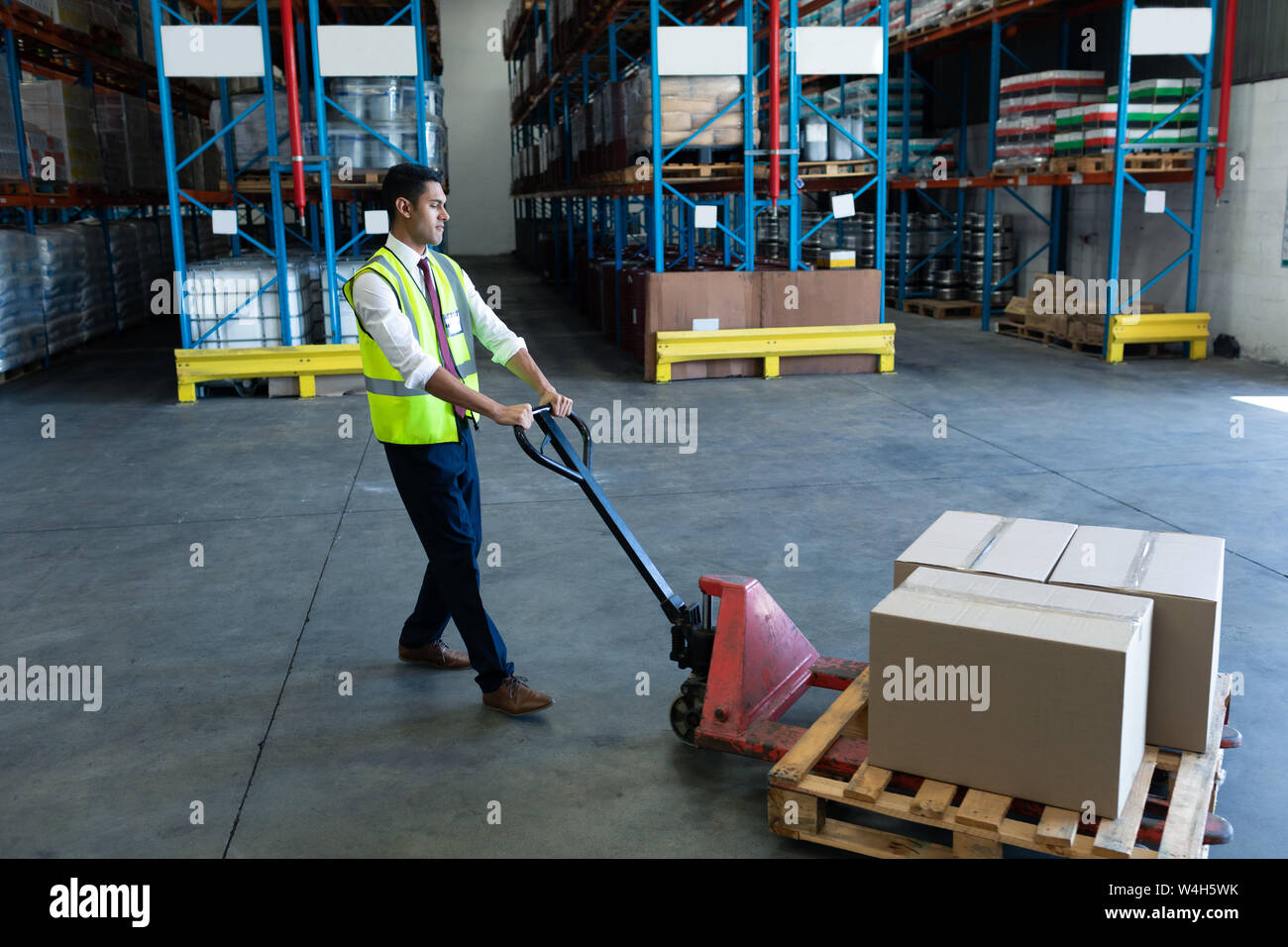 Male staff using pallet jack in warehouse Stock Photo - Alamy