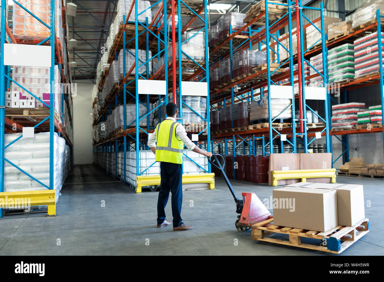 Male staff using pallet jack in warehouse Stock Photo - Alamy