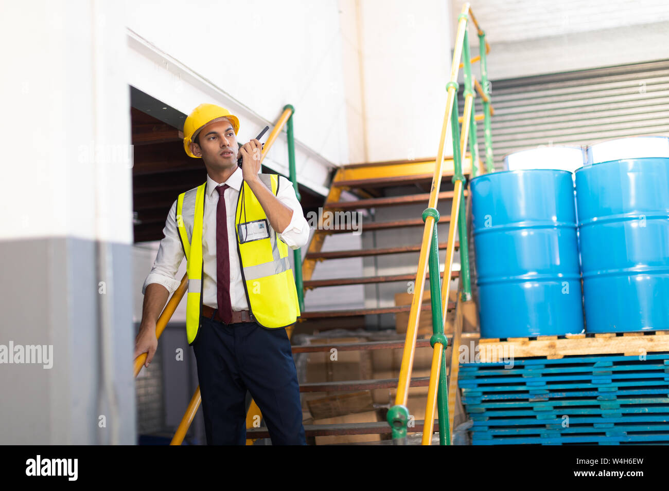 Male supervisor talking on walkie talkie on stairs in warehouse Stock ...