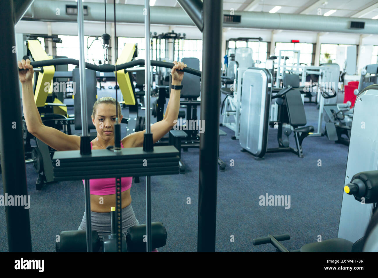 Female athlete exercising with lat pulldown machine in fitness studio ...