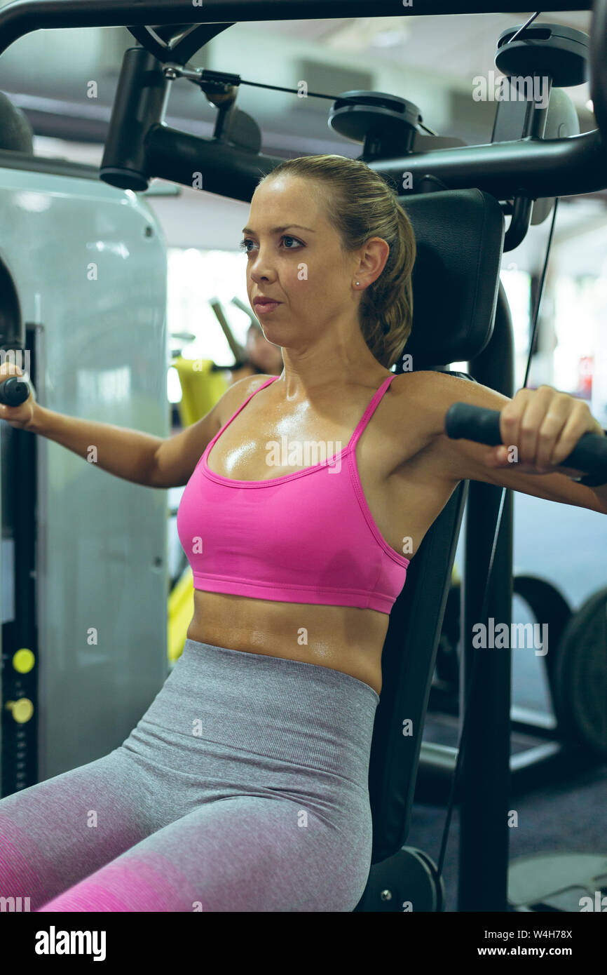 Female athlete exercising with chest press machine in fitness studio ...