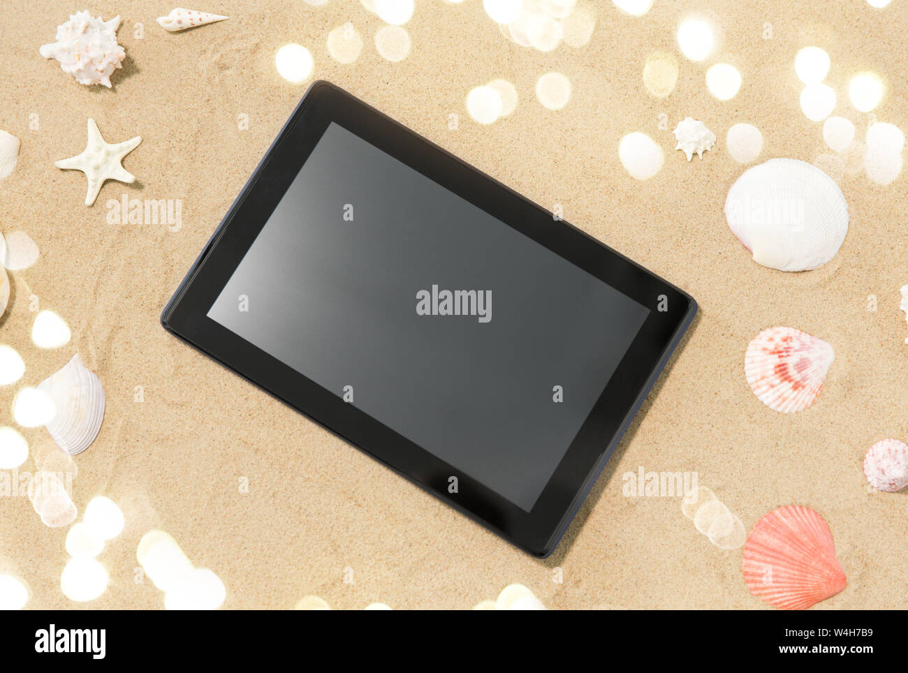 tablet computer and seashells on beach sand Stock Photo - Alamy