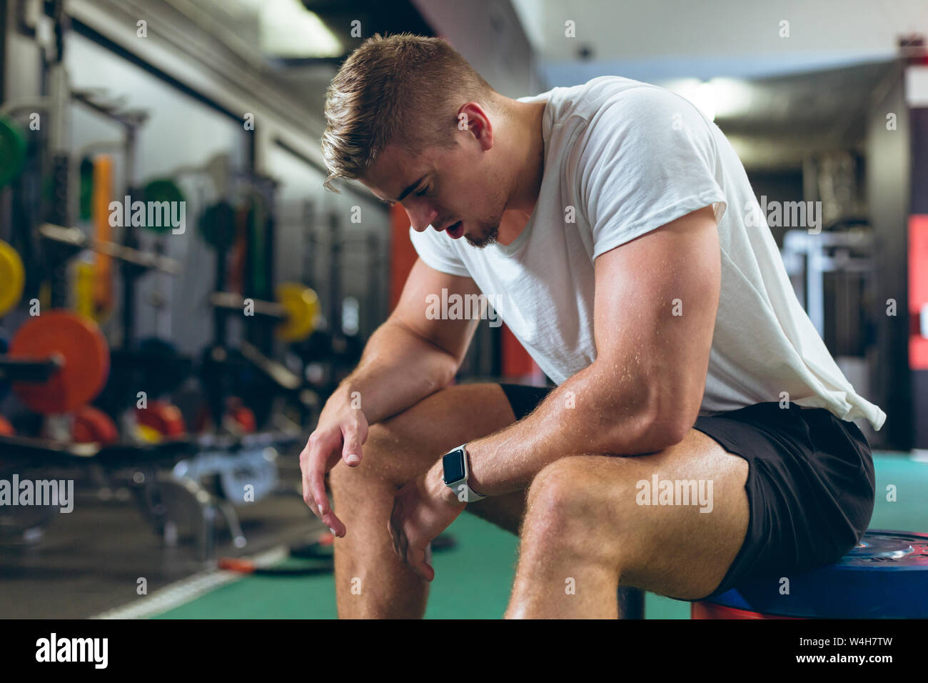 Tired male athlete sitting in fitness center Stock Photo - Alamy