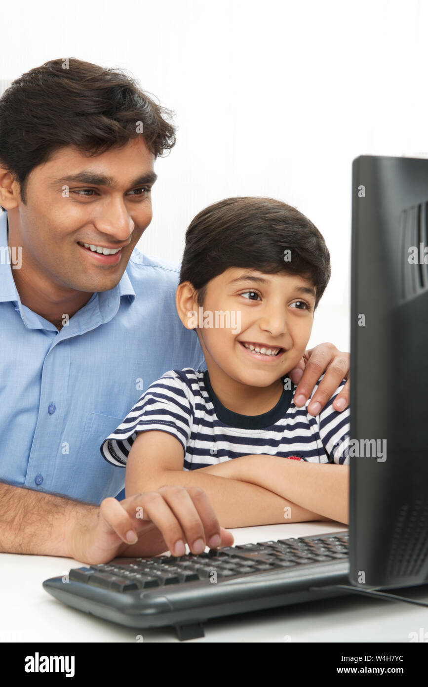 Indian man with his son using a computer at home Stock Photo - Alamy