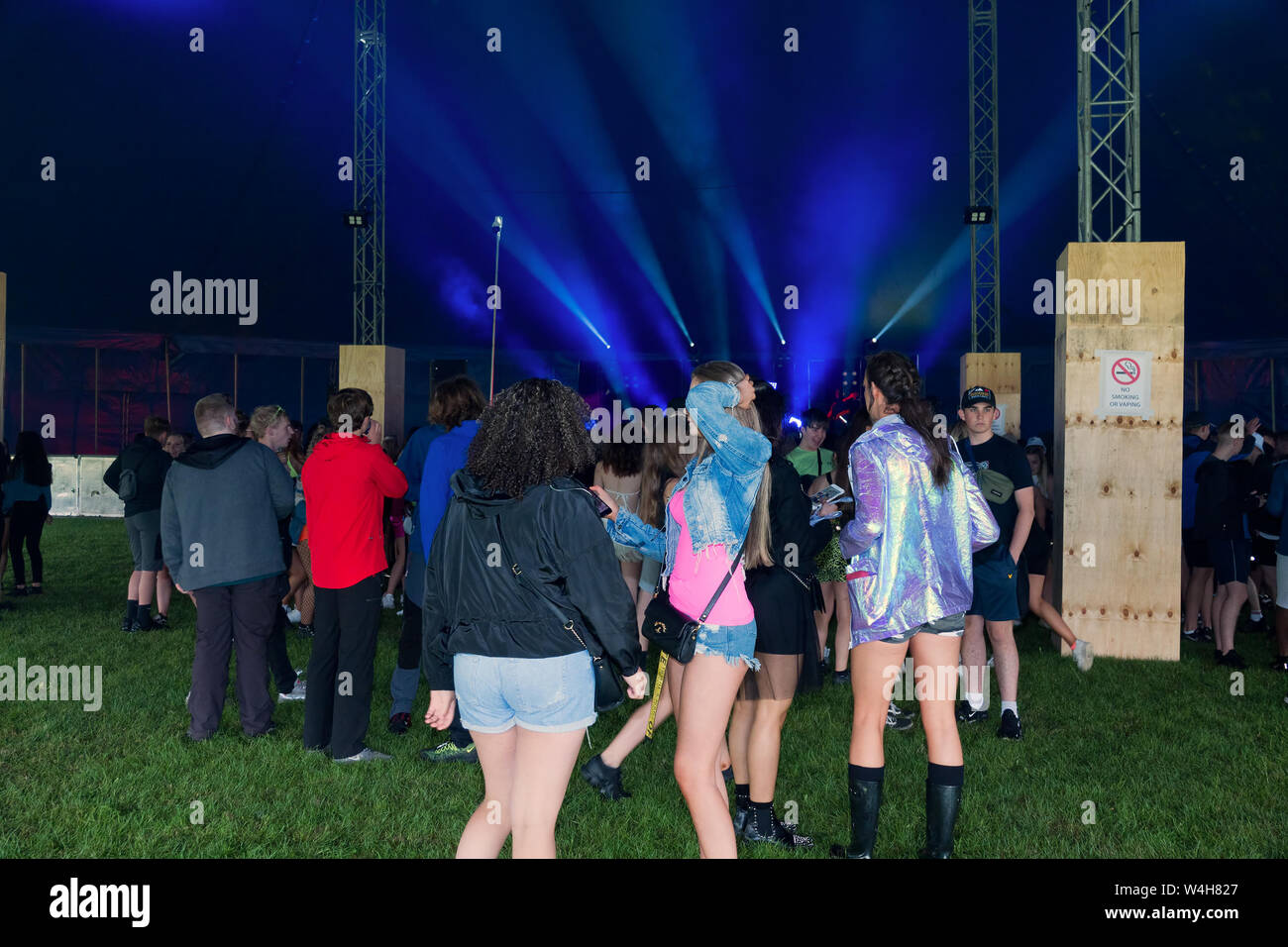 Teenagers listening to rave music in a big marque at an outdoor music ...
