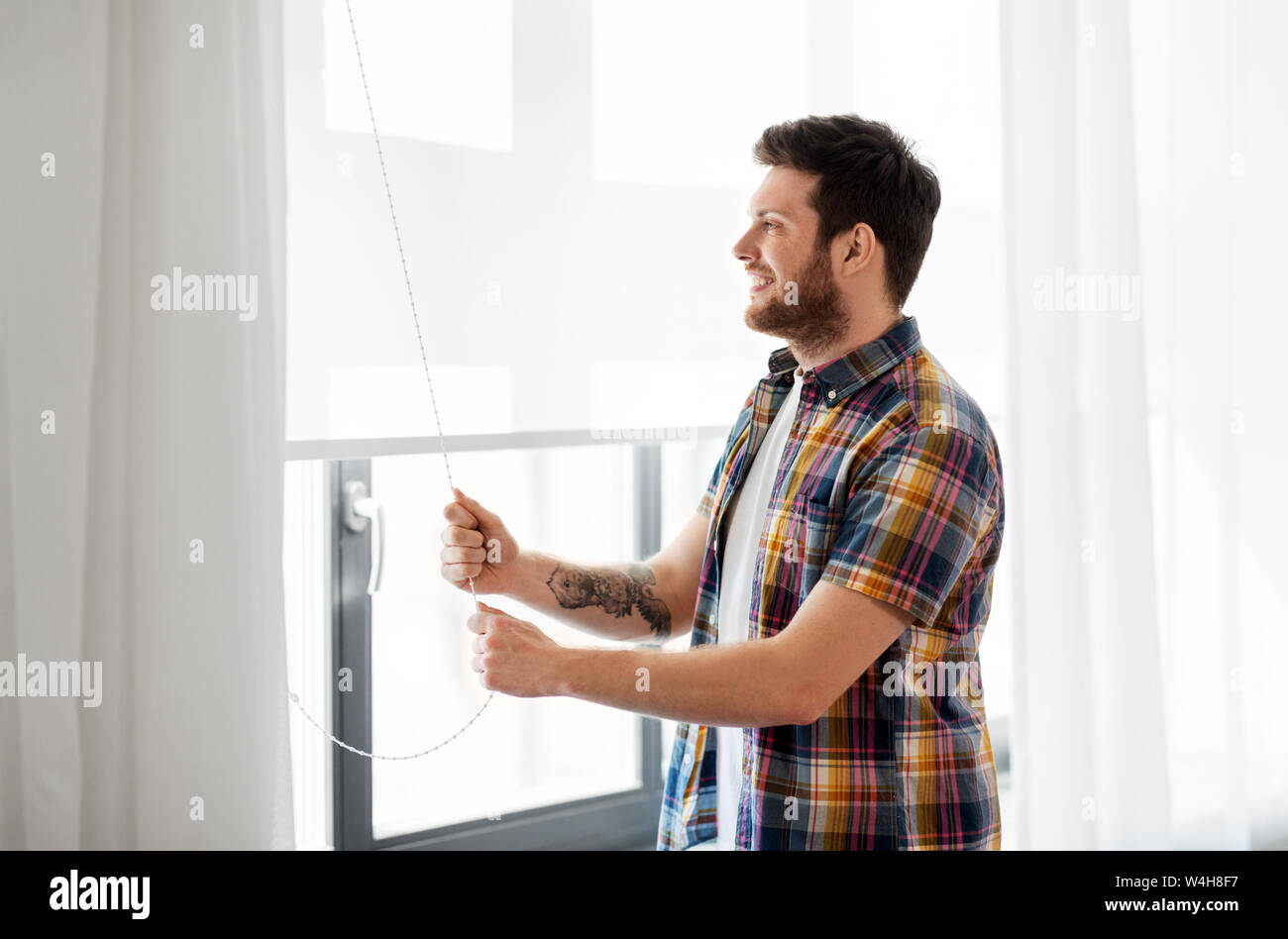man opening roller blind on window at home Stock Photo - Alamy