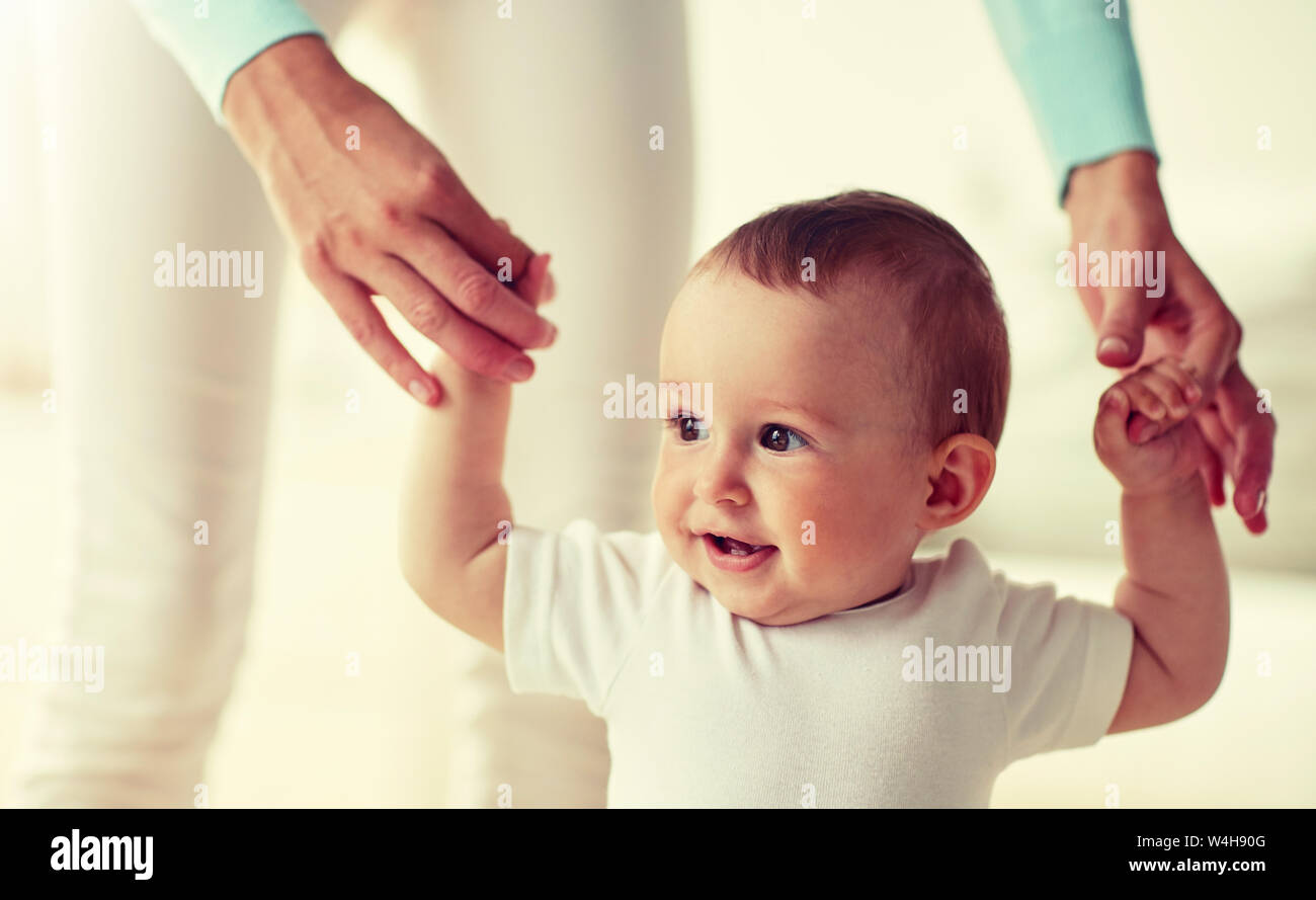 happy baby learning to walk with mother help Stock Photo - Alamy
