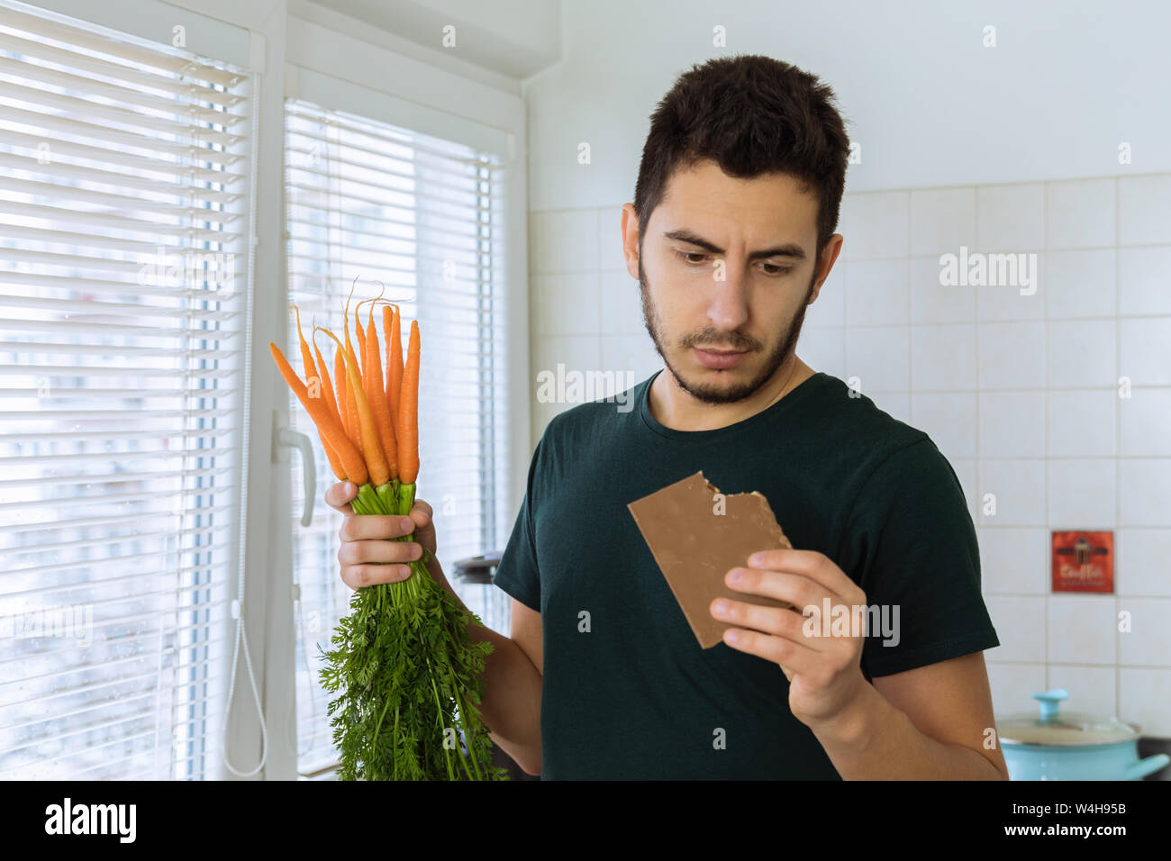 A young handsome brunette man looks at chocolate with disdain and ...