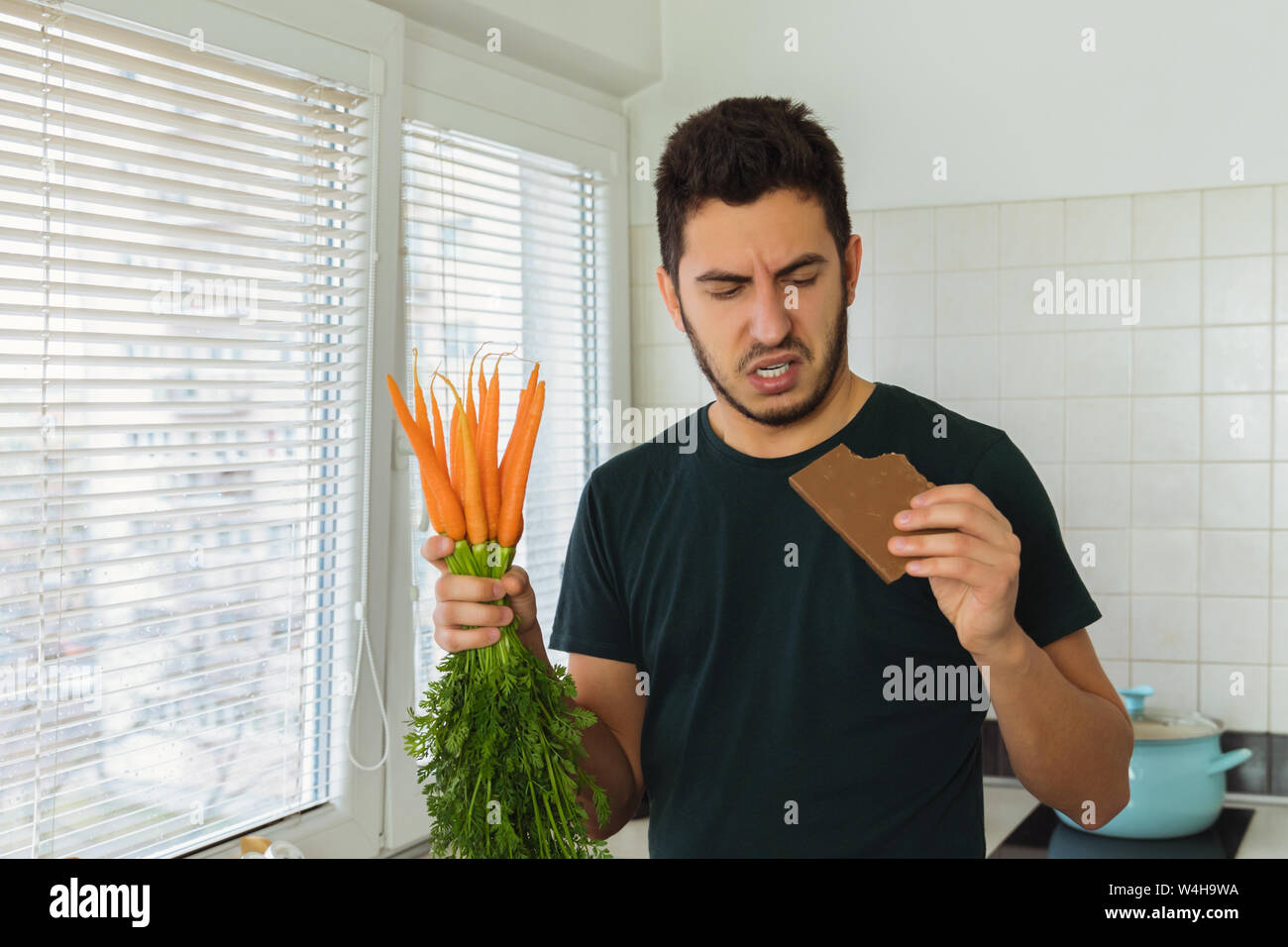A young handsome brunette man looks at chocolate with disdain and ...