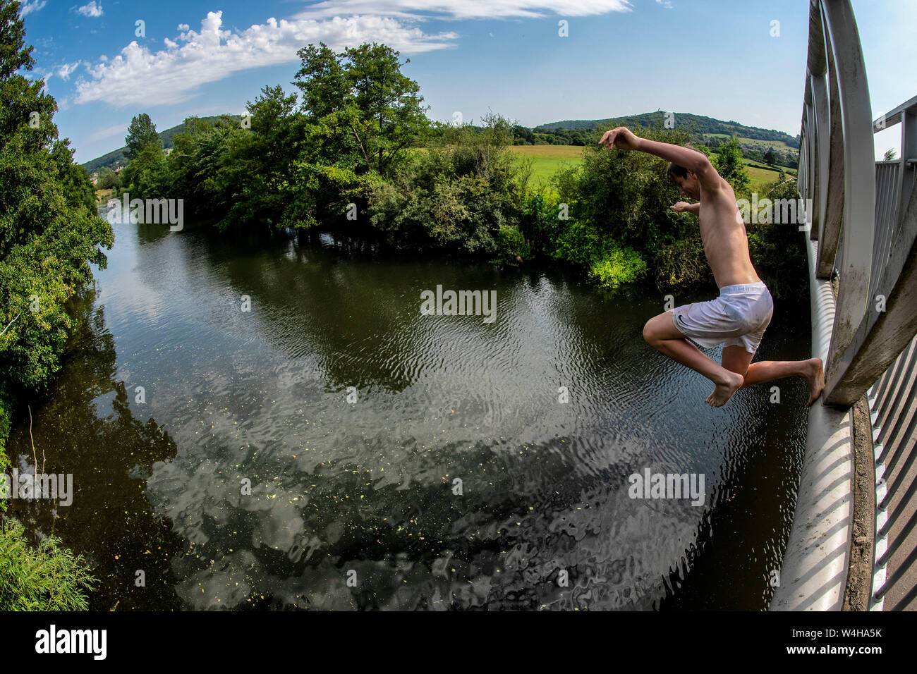 A teenage boy jumps from a footbridge into the River Avon at Batheaston ...