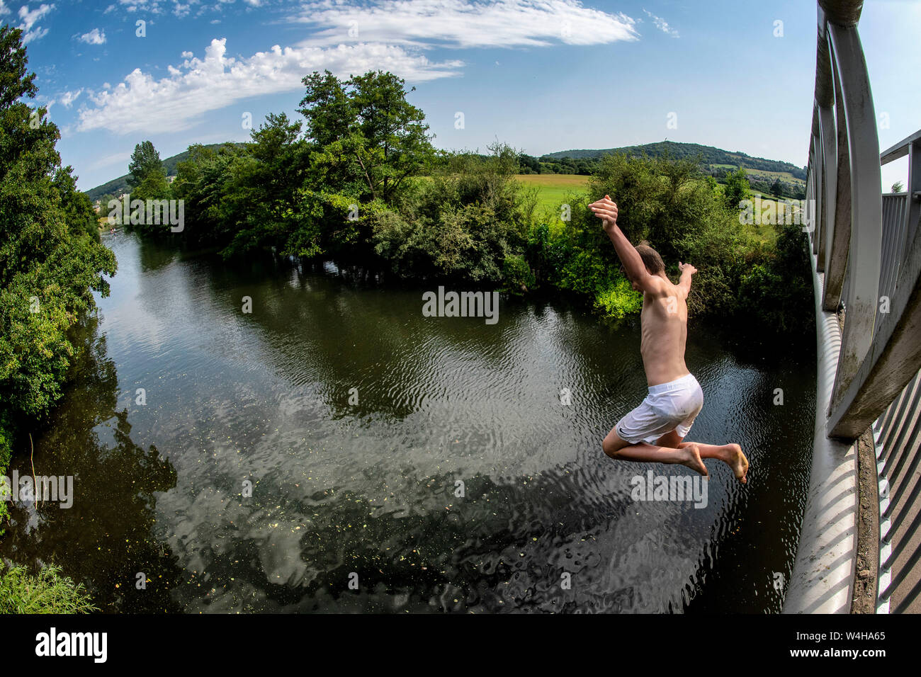 A teenage boy jumps from a footbridge into the River Avon at Batheaston ...