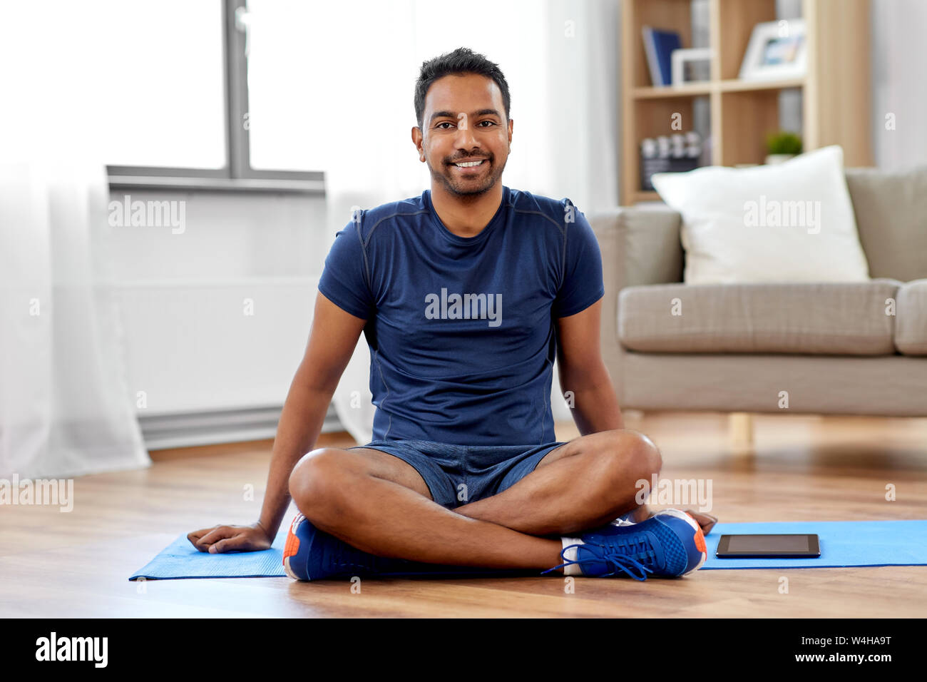 smiling indian man sitting on exercise mat at home Stock Photo - Alamy