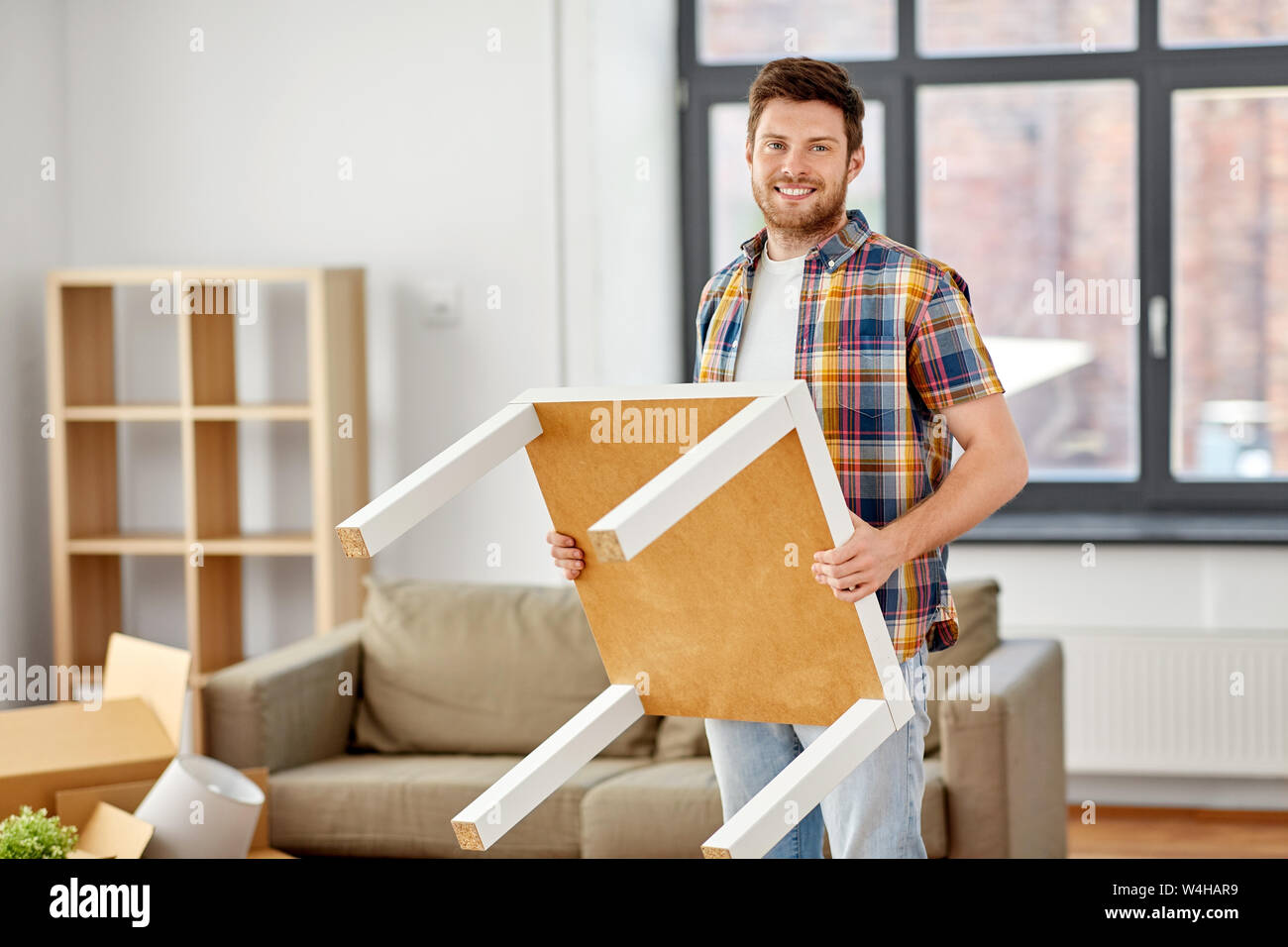 happy man with table moving to new home Stock Photo - Alamy
