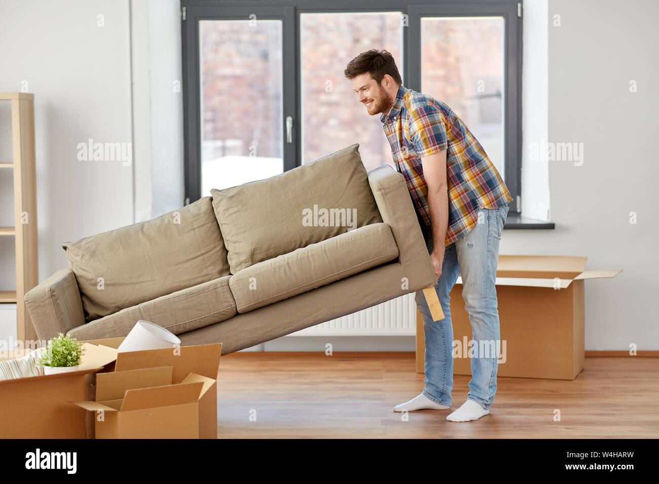 happy man moving sofa at new home Stock Photo - Alamy