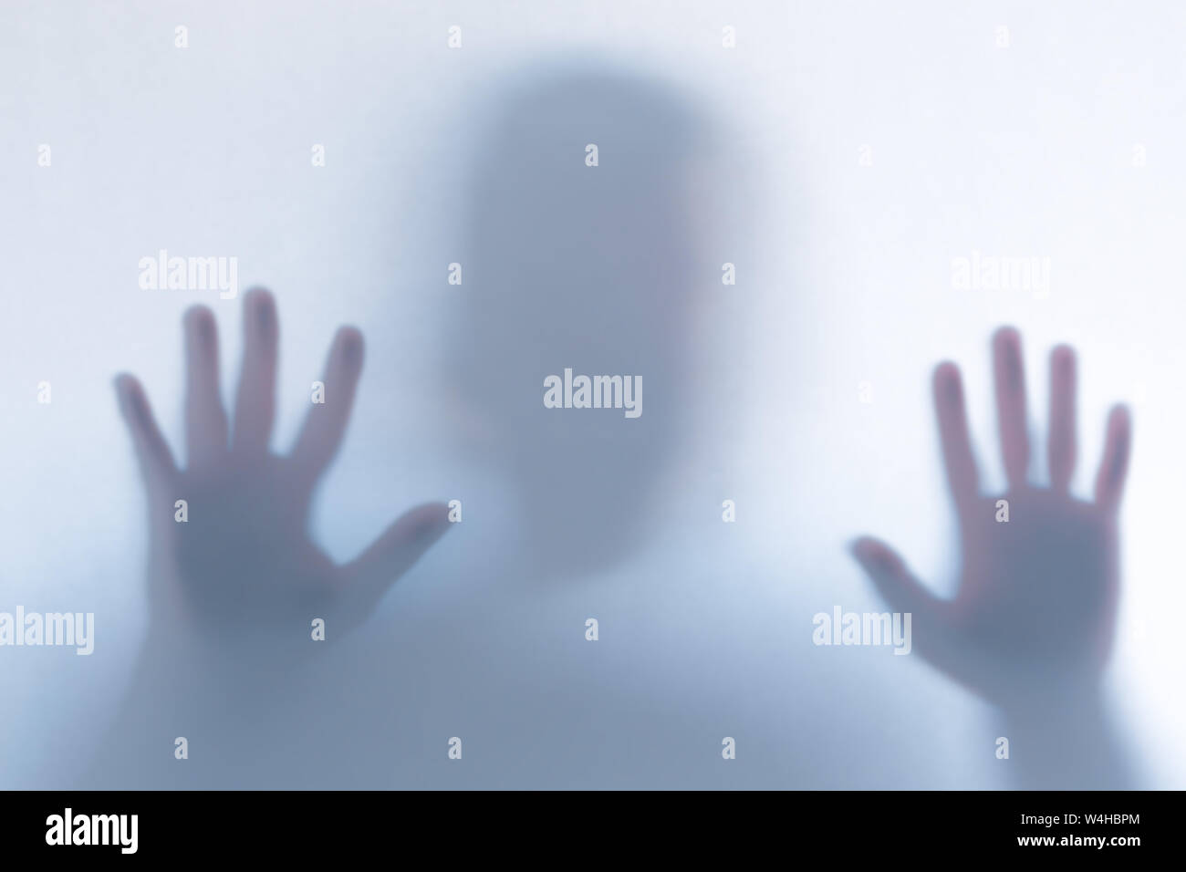 Blurred scary ghost silhouette behind a white glass background ...