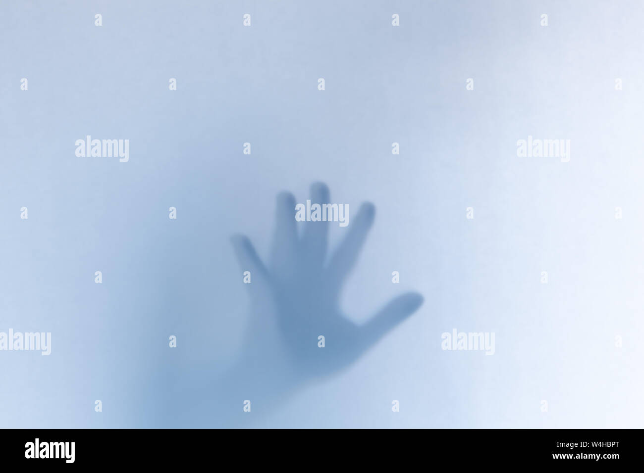 Blurred scary ghost hands behind a white glass background. Horizontal ...