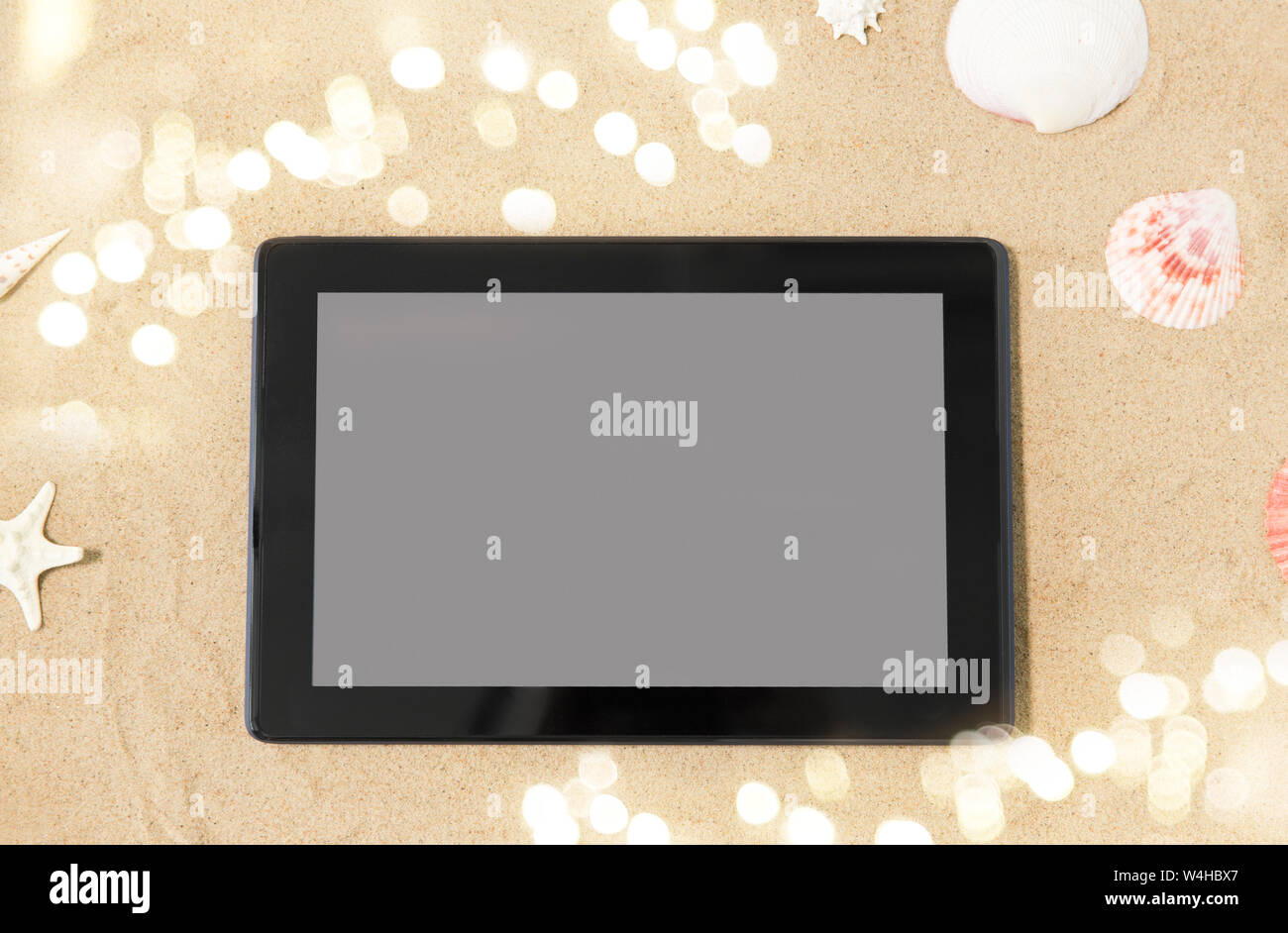 tablet computer and seashells on beach sand Stock Photo - Alamy