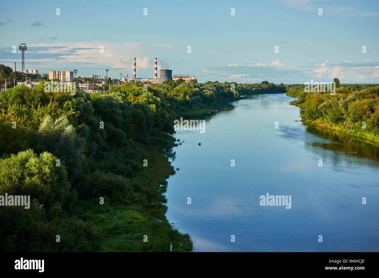 Wide river with forest and industrial buildings in the background Stock ...