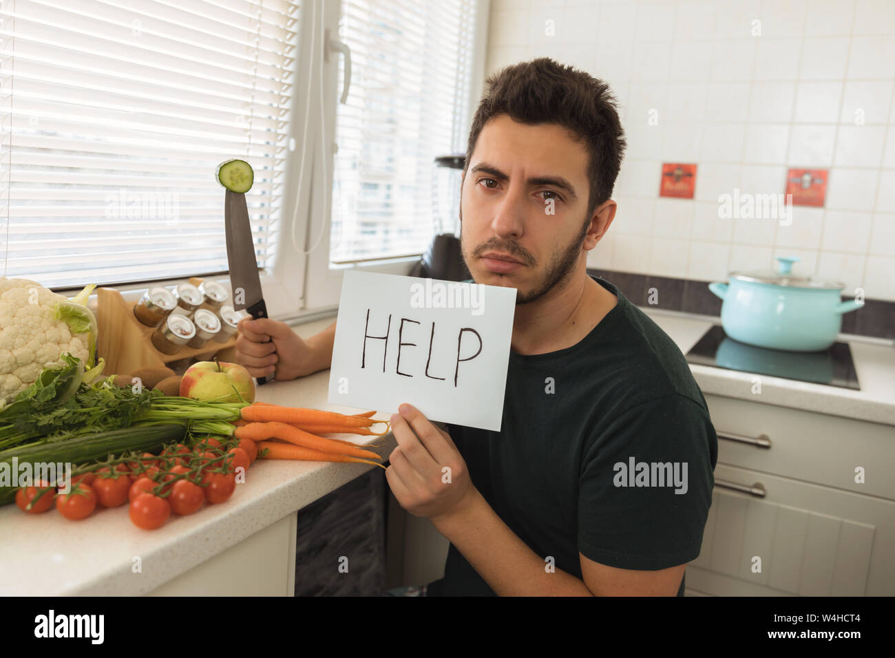 A young handsome man sits in the kitchen with a sad face and asks for ...