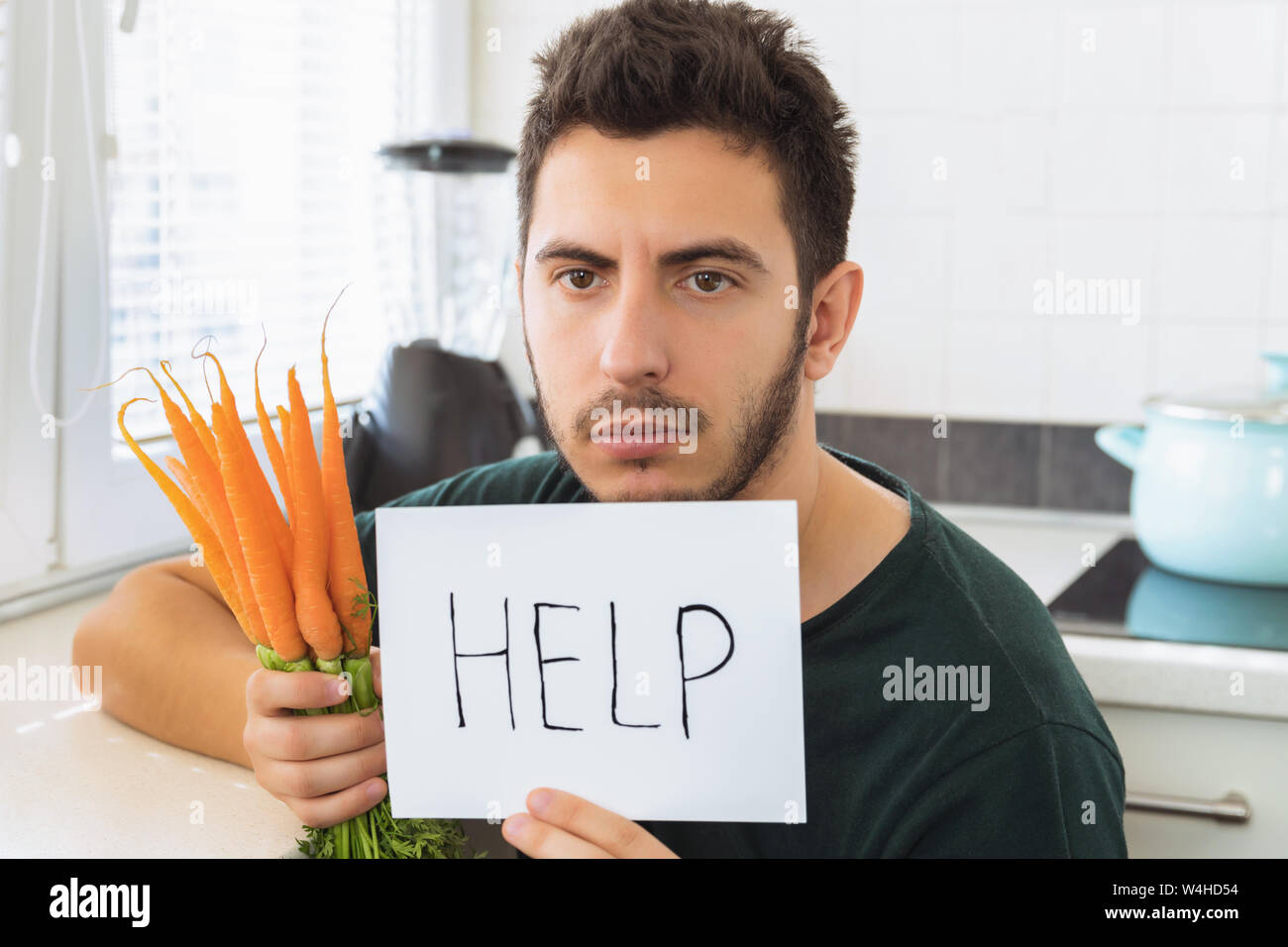 A young handsome man sits in the kitchen with a sad face and asks for ...
