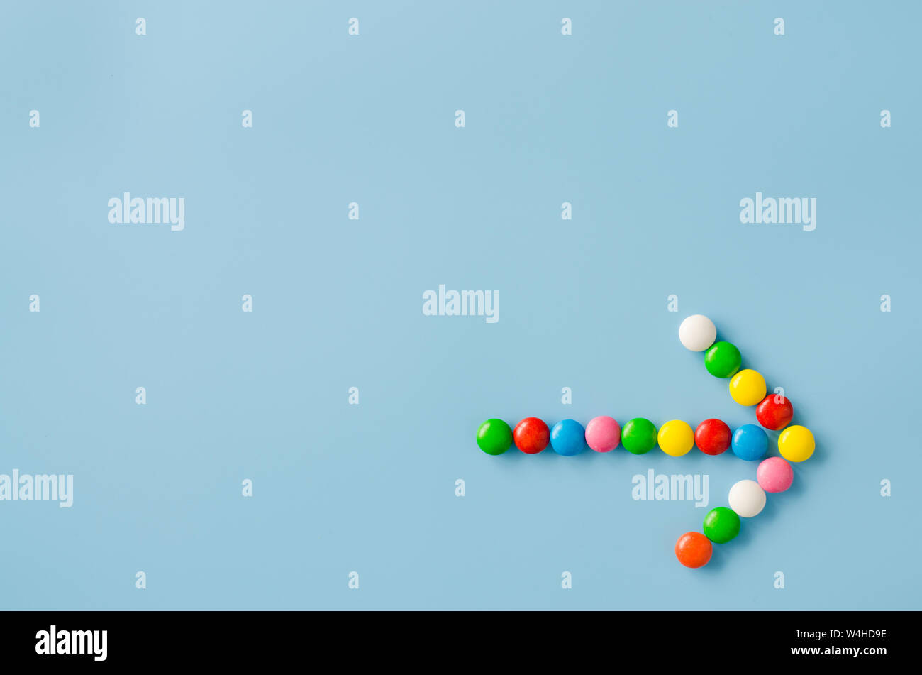 Pointer arrow of multicolored chocolate candy with colored glaze on a ...