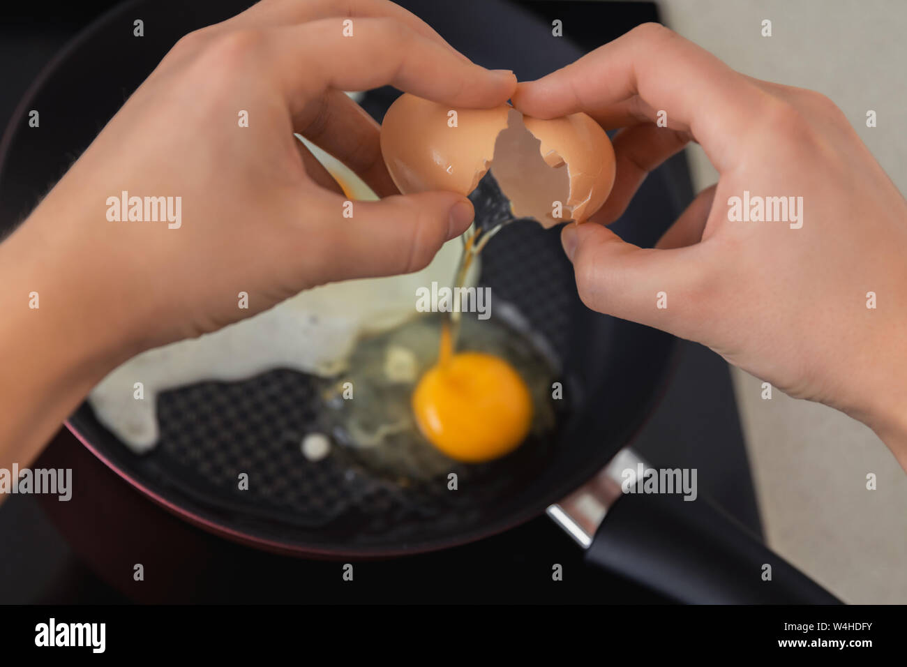 A man cooks scrambled eggs for breakfast. Broken chicken eggs in a pan ...