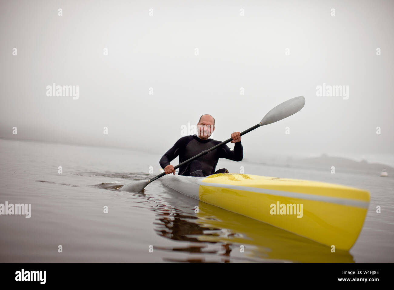Male kayaker smiles for a portrait as he paddles in the waters of a ...