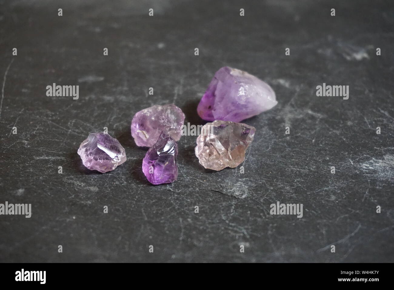 Uncut and raw amethyst crystals on grey slate background Stock Photo ...