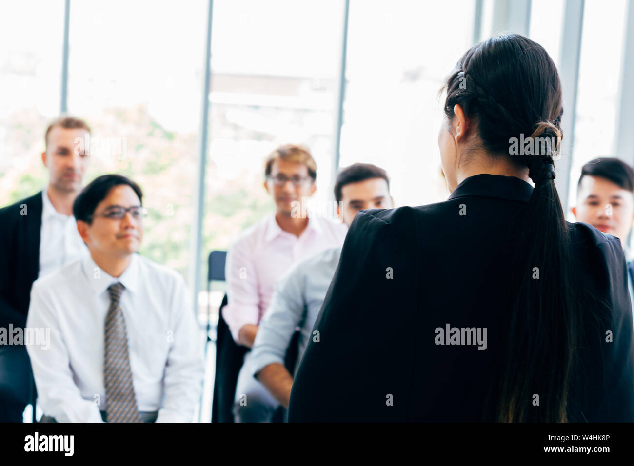 Back view of stylish woman giving presentation for male colleagues ...
