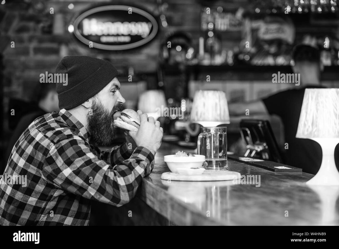 Man with beard eat burger menu. Brutal hipster bearded man sit at bar ...