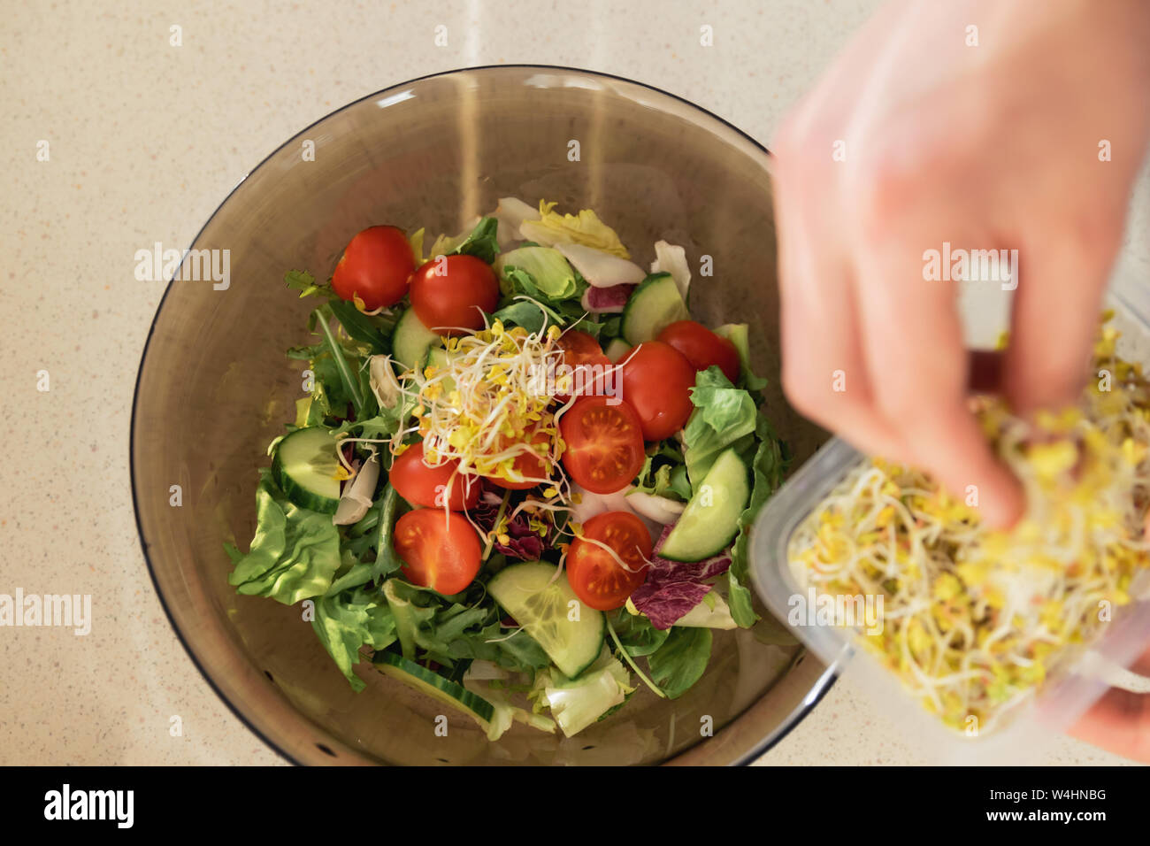 A young man prepares a very healthy salad of fresh organic vegetables ...