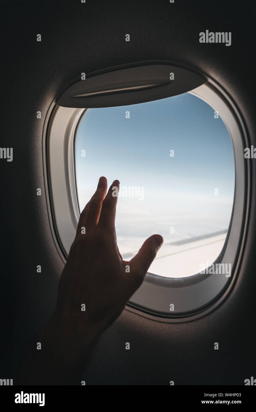 Porthole window in the plane with a man's hand during the flight Stock ...