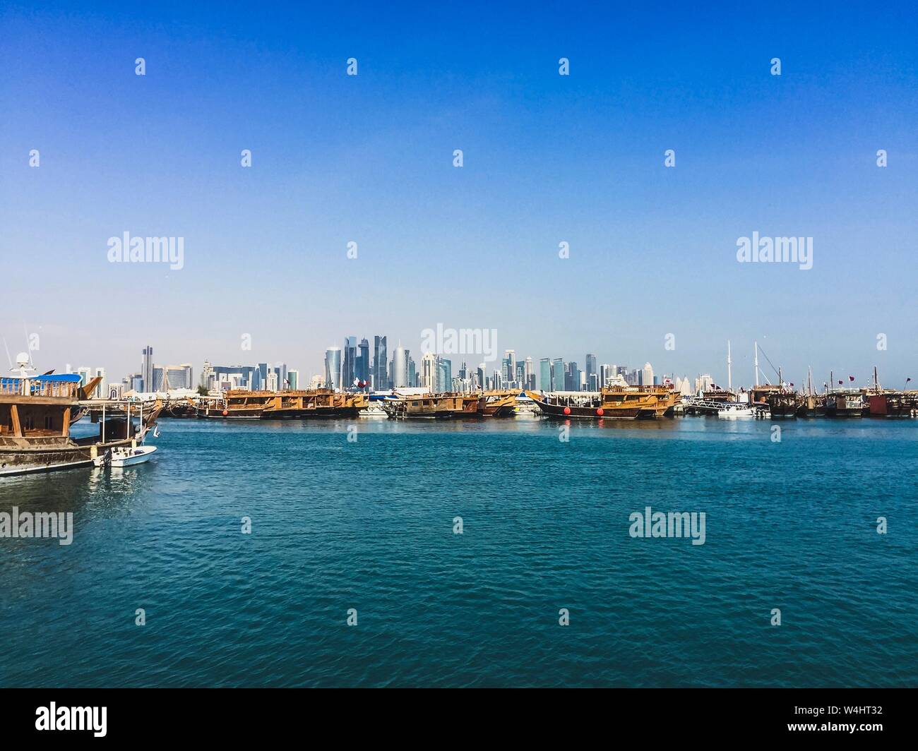 Traditional Arabic dhow boats in the Corniche harbour with the city ...