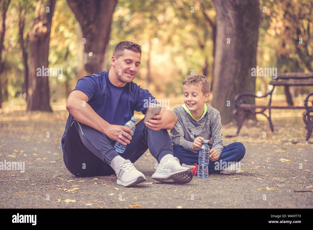 Little boy and his father taking a break after workout and watching ...