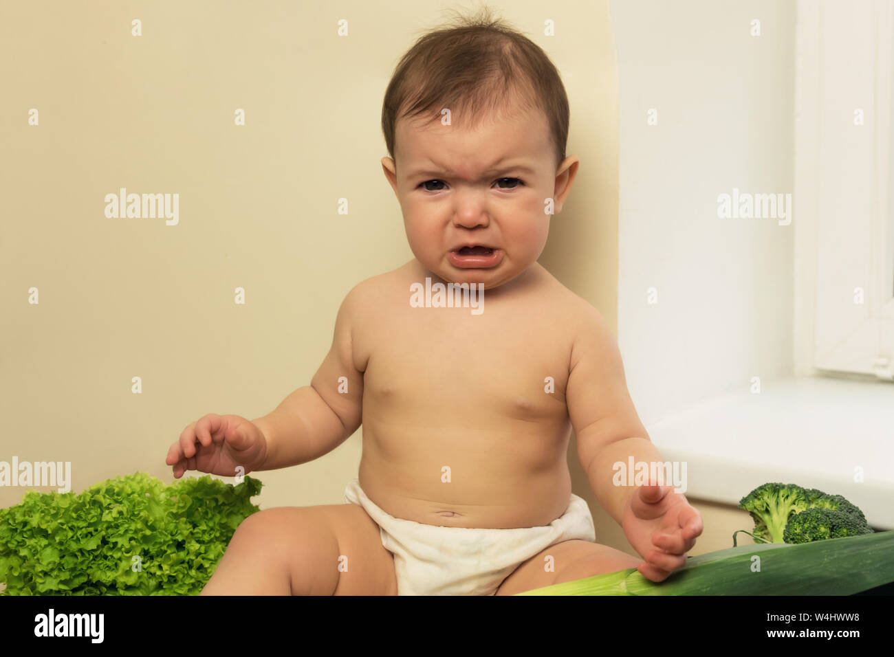 The baby in the diaper is sitting on the kitchen table with fresh ...