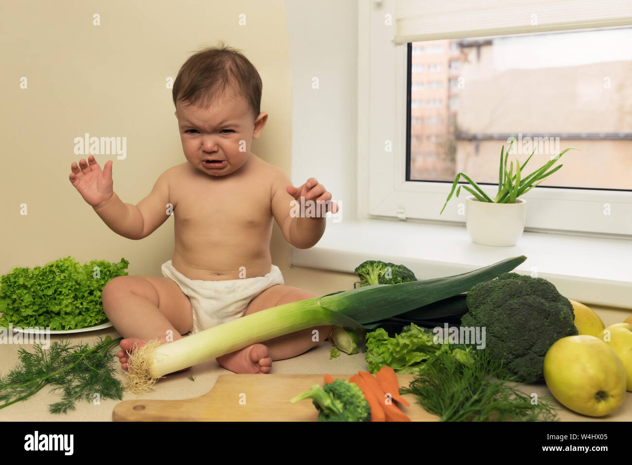 The baby in the diaper is sitting on the kitchen table with fresh ...