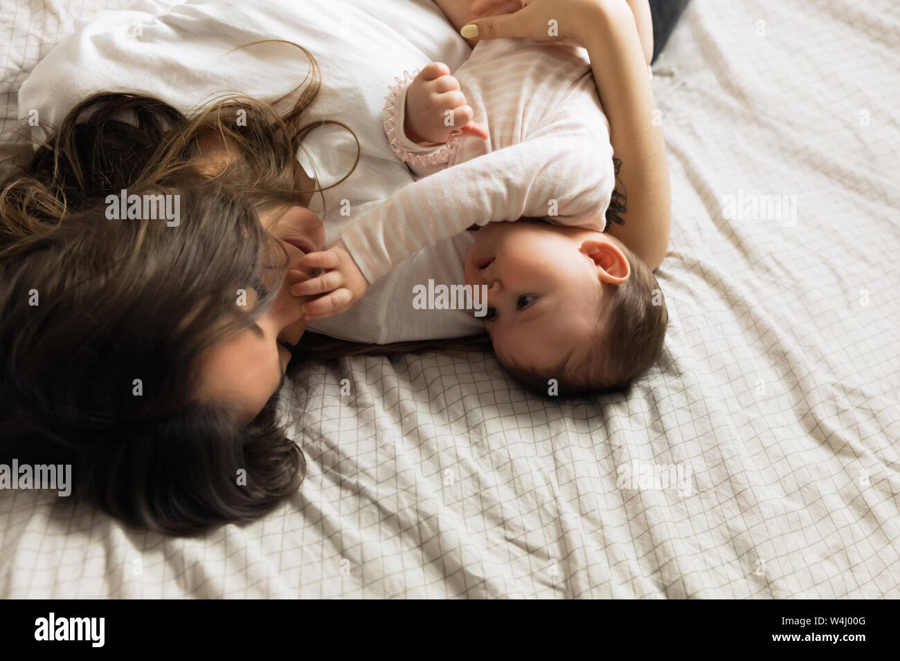 Young mother and baby are in bed. Mom and baby are playing at home ...