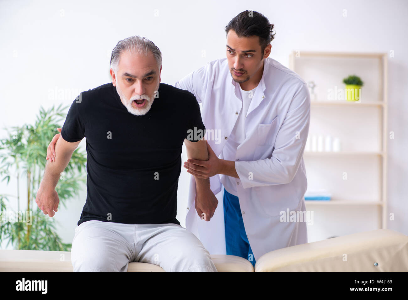 Old injured man visiting young doctor Stock Photo - Alamy