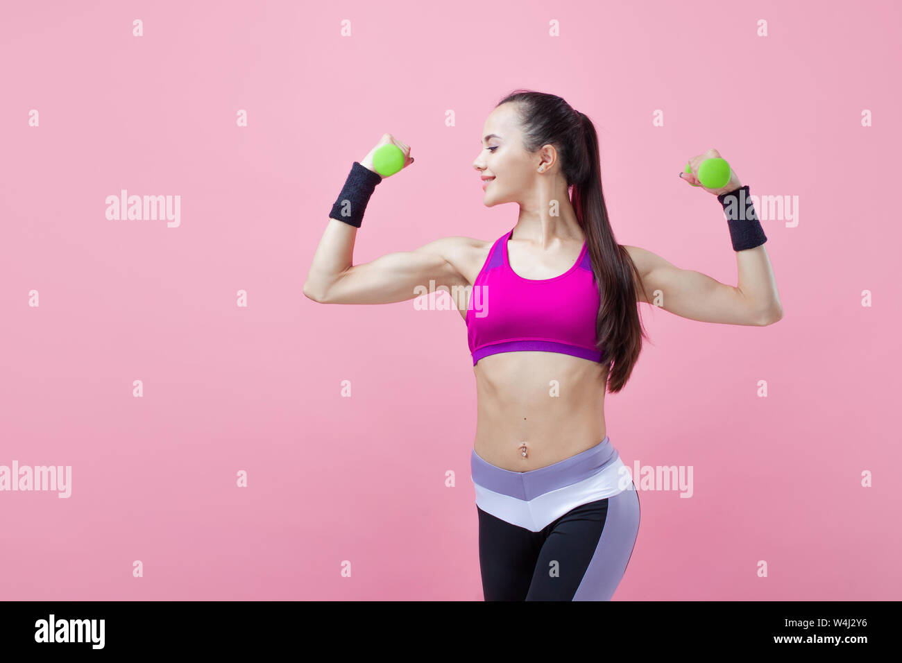 A young athletic brunette girl with a ponytail in a bright top shows ...