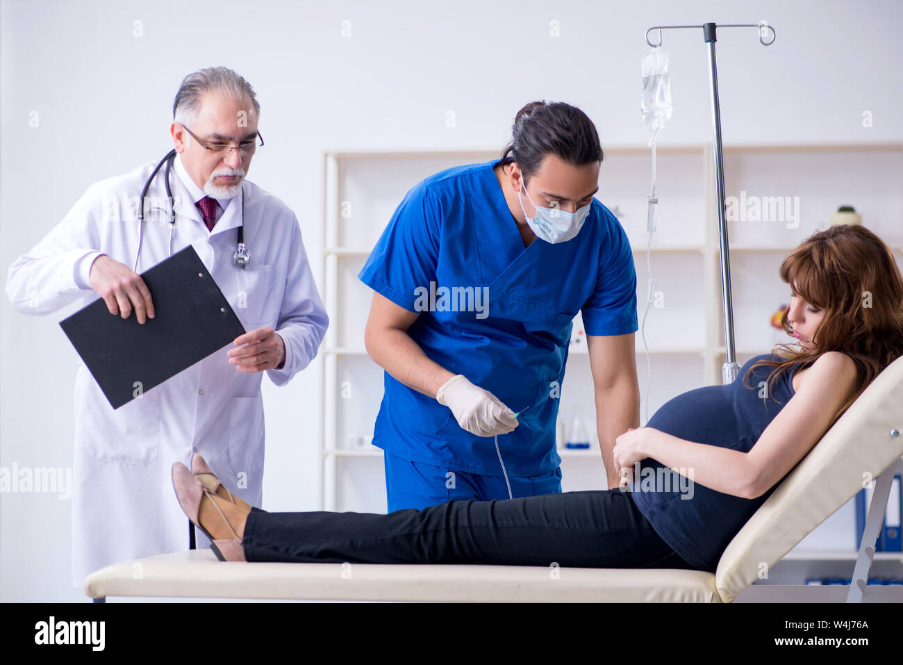 Two doctors examining young woman Stock Photo - Alamy