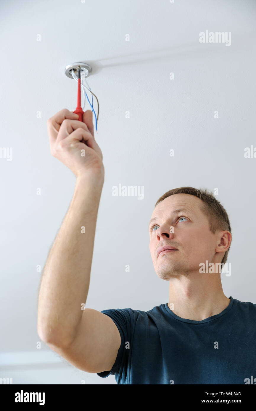 Installing a spotlight in the room. The man is fixing the bracket for ...