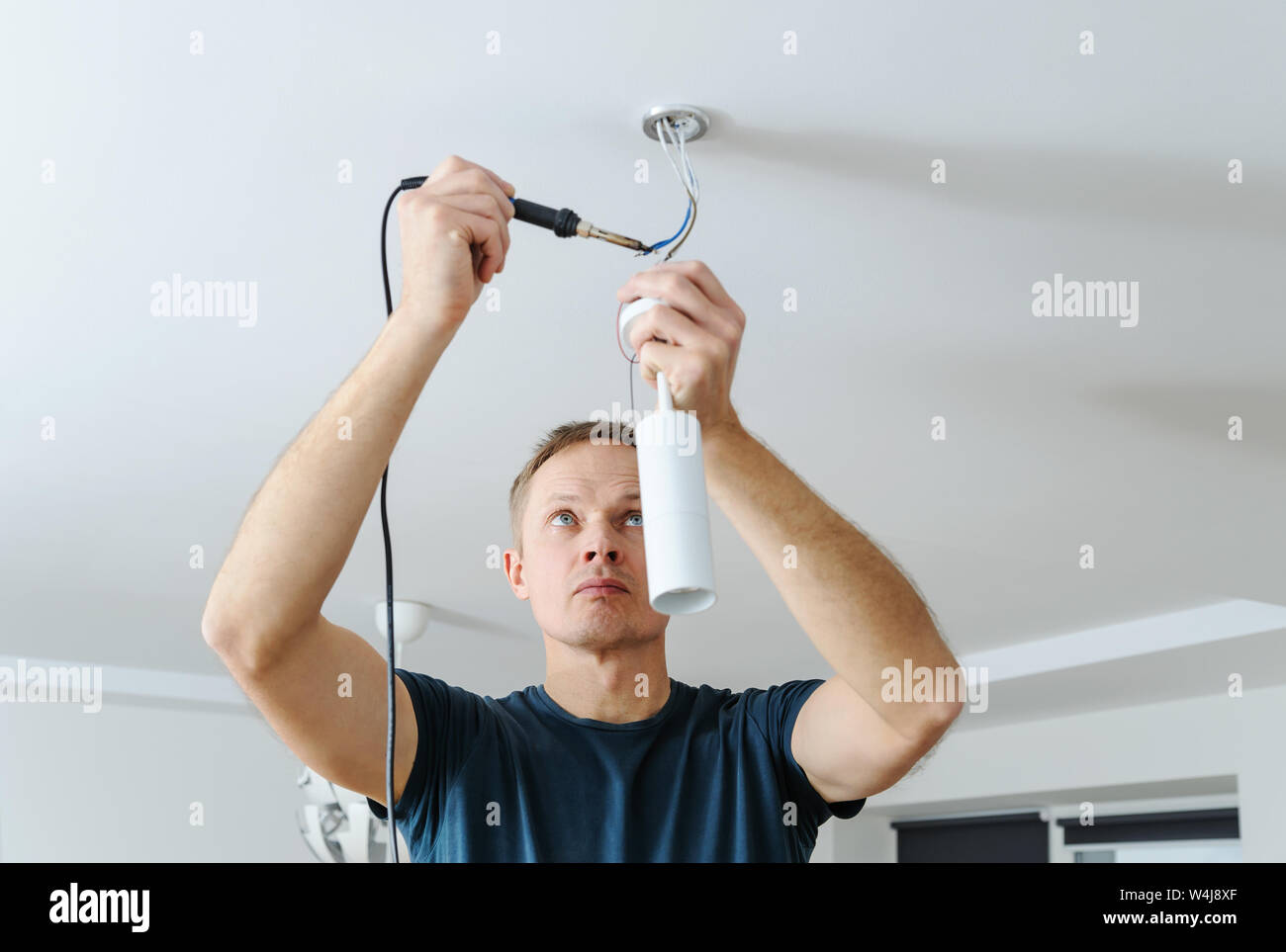Installing a spotlight in the room. The man is a soldering wire Stock ...