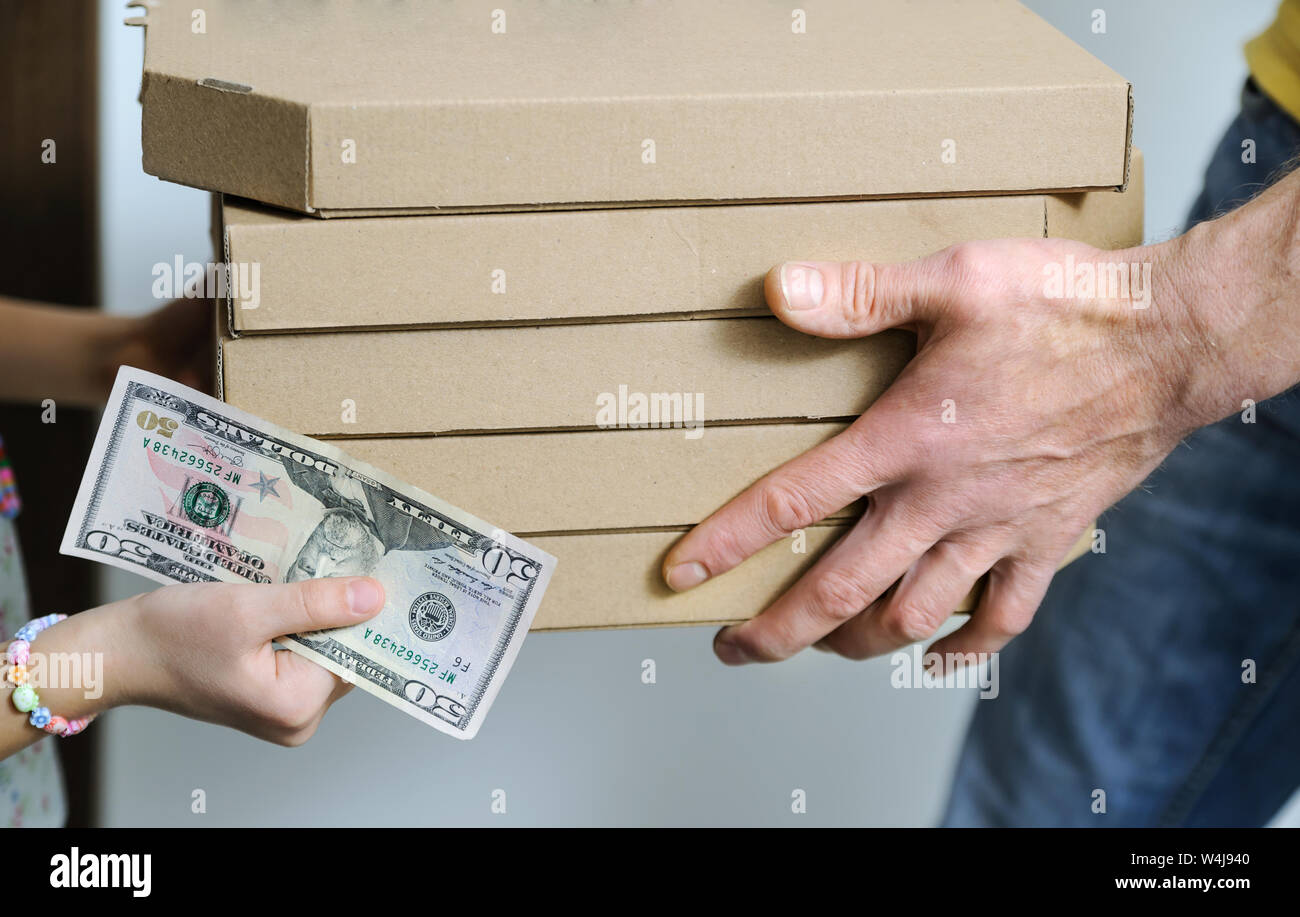 Food delivery home. The girl is taking boxes from the pizza deliverer ...