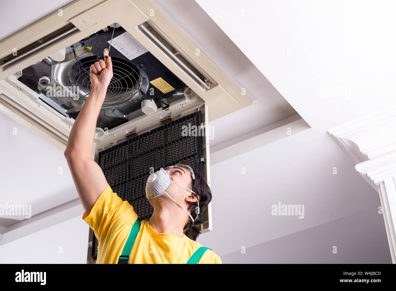 Young repairman repairing ceiling air conditioning unit Stock Photo - Alamy