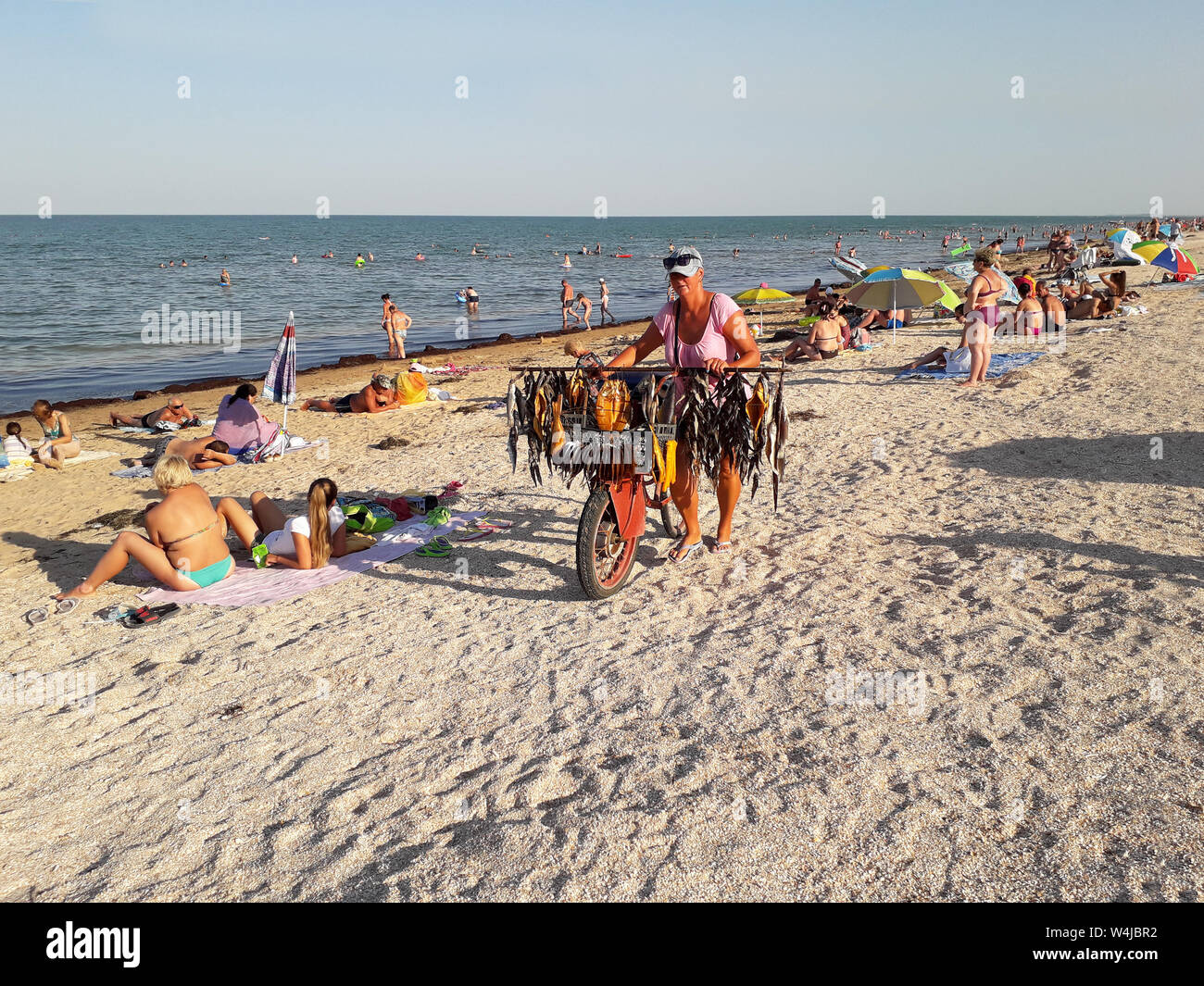 Saleswoman of salted and dried fish on the beach in the Kirillovka town ...