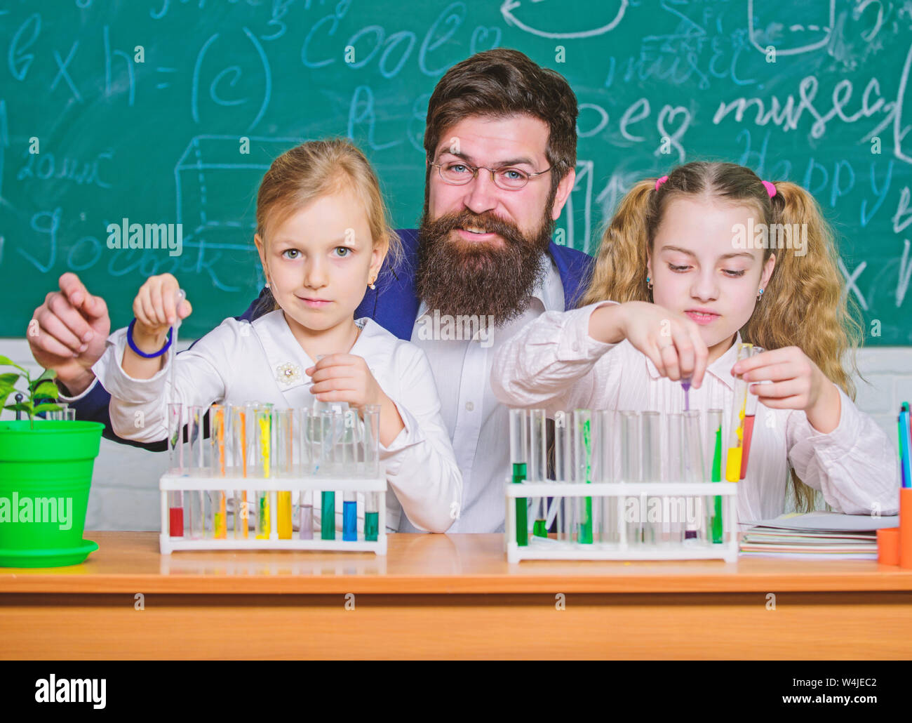 School time. Schoolgirls holding test tubes guided by teacher. School ...