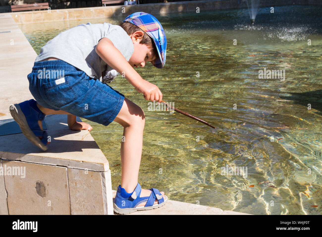 Child creeping with wet twig on marble pool edge Stock Photo - Alamy