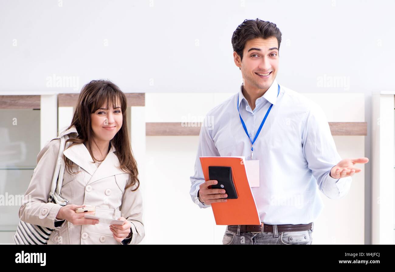 Salesman explaining to woman customer at furniture store Stock Photo ...