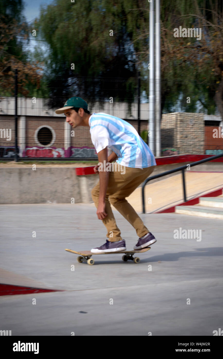 A boy wearing an argentinian football shirt skating at the skate park ...