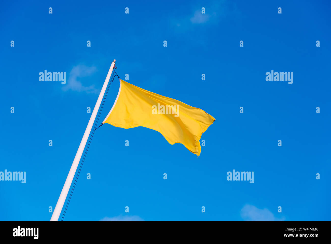 Yellow fabric flag waving to the wind with the background of a clear ...